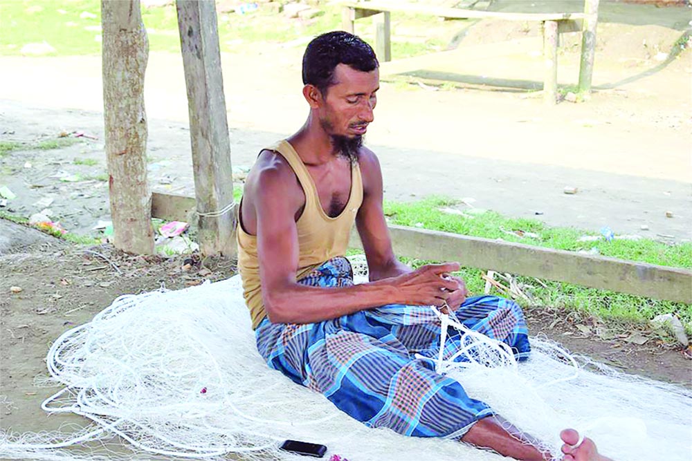 Fishers weaving net to pass idle time at Char Fasson